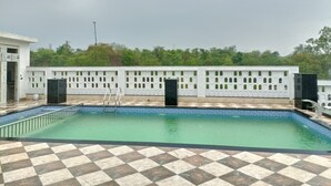 Uma piscina com piso xadrez, rodeada por uma parede branca com elementos decorativos.