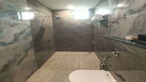 Um banheiro moderno com chuveiro, vaso sanitário e parede de mármore.