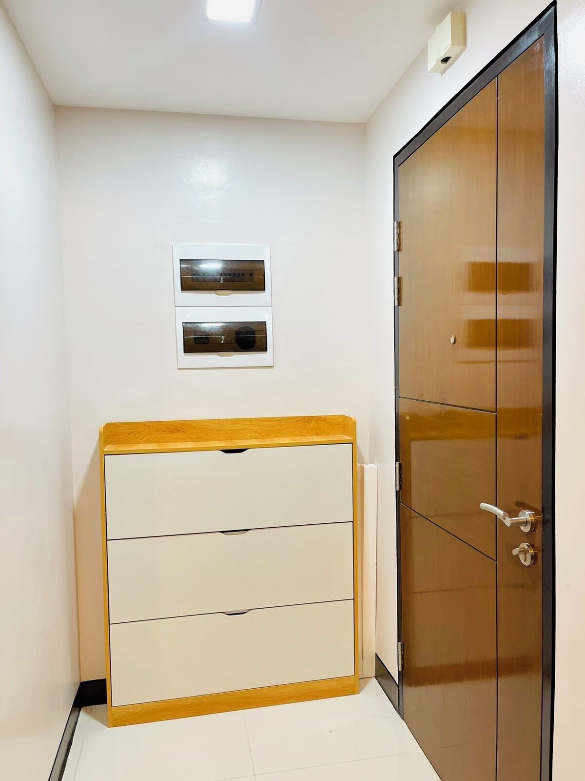 Quarto com cama de cabeceira em madeira, porta de correr de vidro e uma pequena prateleira na parede.
