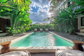 A pool area with lounge chairs and a view of a building in the background.