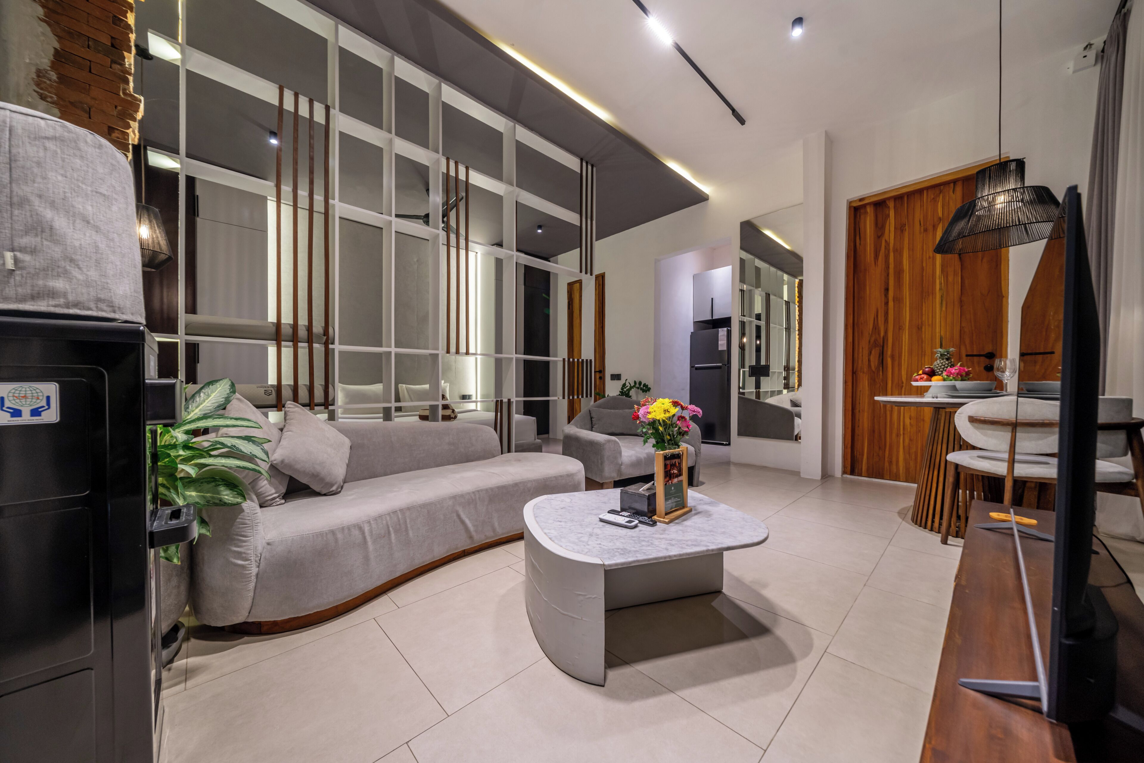Uma sala de estar moderna com sofá, mesa de centro e área de jantar com mesa e cadeiras de madeira.