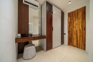 Quarto moderno com toucador de madeira, um espelho, um banquinho pequeno e um guarda-roupa com porta de madeira.