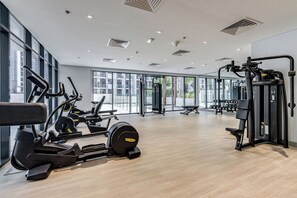 Uma academia moderna com diversos equipamentos de exercício, amplas janelas e um interior espaçoso e limpo.