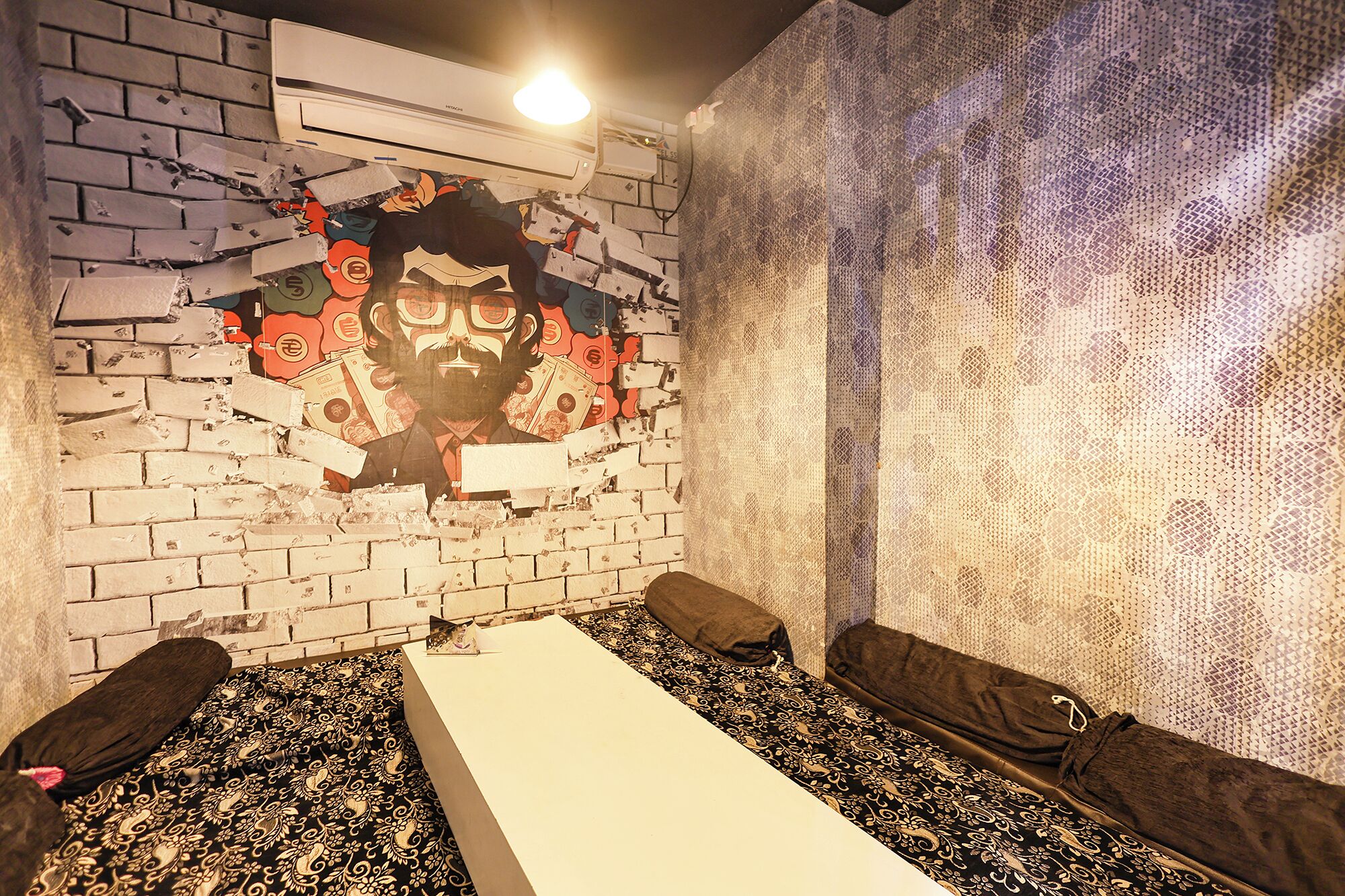 Quarto com parede de tijolos, uma mesa branca e cortina estampada.
