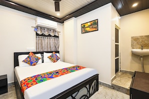 Quarto de hotel com uma cama, um quadro, um banheiro com pia e um aparelho de ar condicionado.