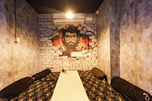 Quarto com uma mesa comprida e branca, dois sofás pretos e uma parede com um grande mural.
