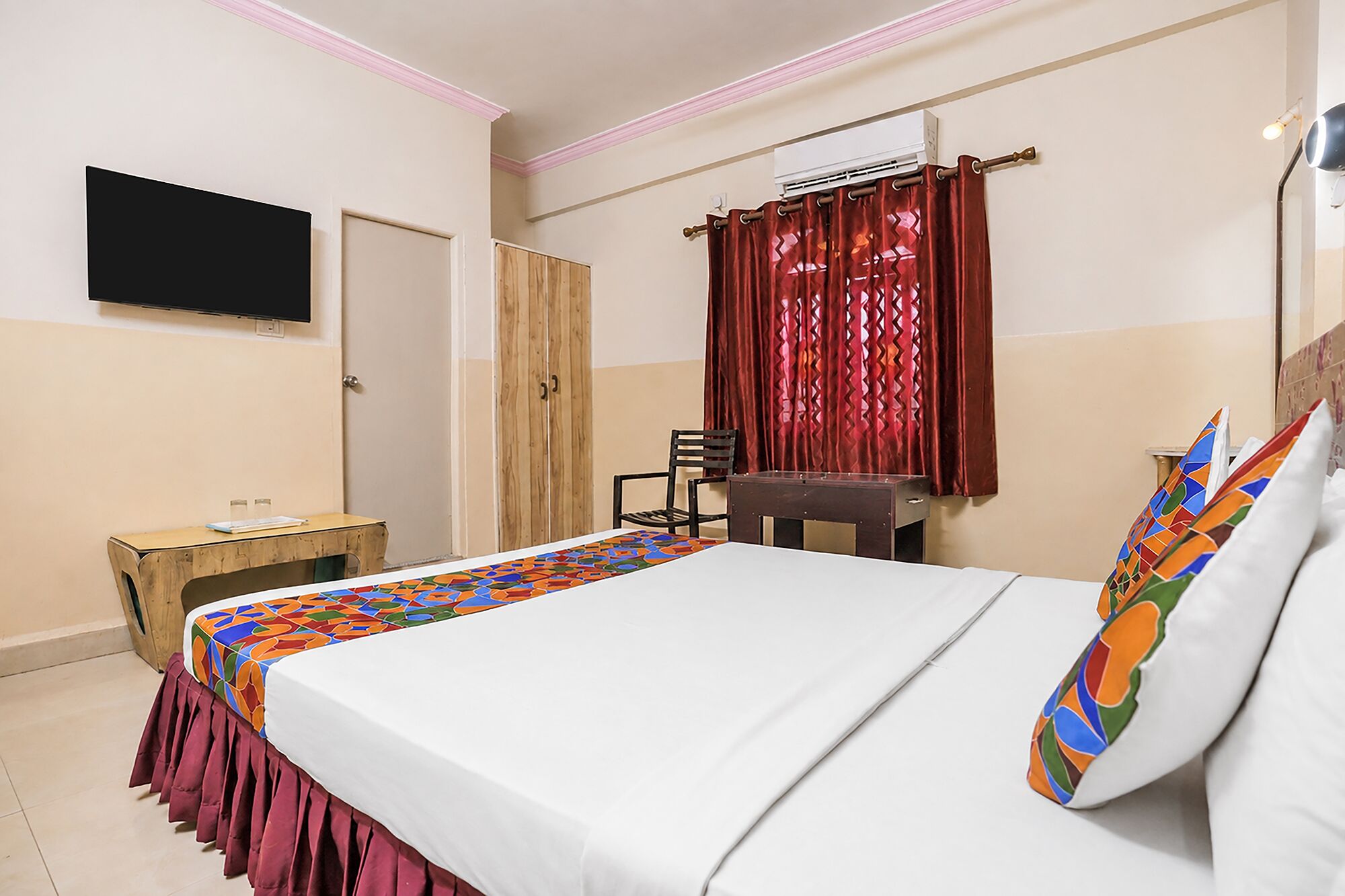Um quarto com cama, escrivaninha, cadeira, guarda-roupa e televisão.