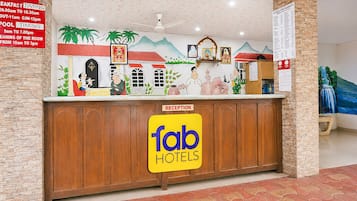 Uma receção com o sinal da Fab Hotels, um sinal de proibido fumar e uma parede com um mural.