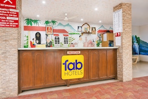 Uma receção com o sinal da Fab Hotels, um sinal de proibido fumar e uma parede com um mural.