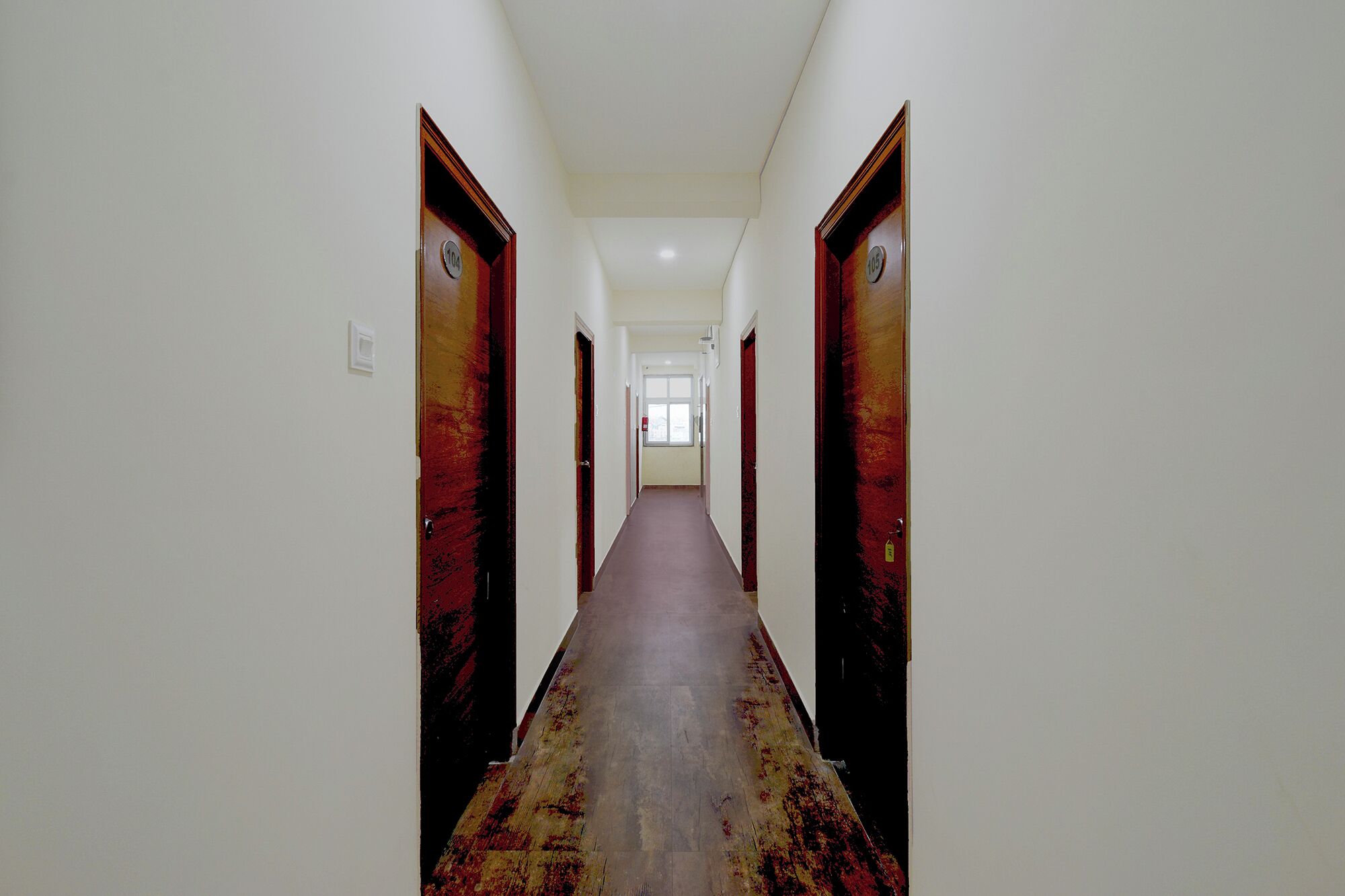 Um corredor comprido e estreito, com portas em ambos os lados e piso coberto de carpete.