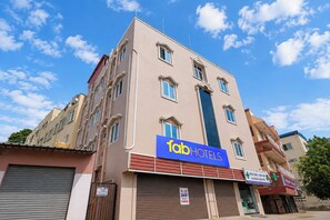 Um hotel de vários andares com uma placa grande da marca 'fab hotels', uma fachada visível e o letreiro de uma loja fechada.