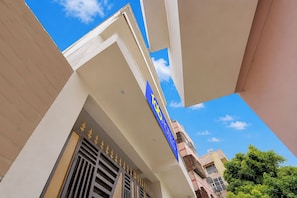 Um hotel com um céu azul límpido ao fundo, exibindo uma placa azul com letras douradas.