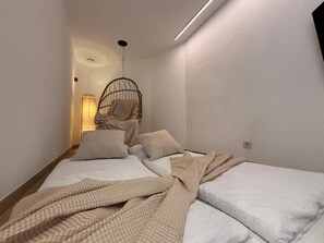 Um quarto com uma cama, uma cadeira suspensa e um abajur.