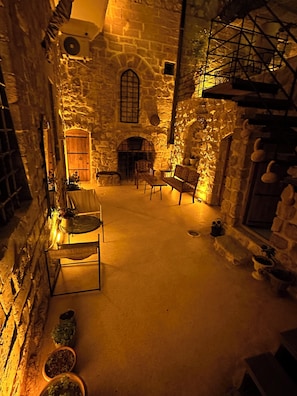 Um quarto com paredes de pedra, lareira, móveis de madeira e plantas em vasos.