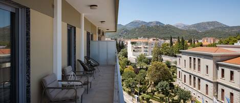 Varanda com assentos e vista para a paisagem urbana e montanhas.