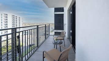 Uma varanda com vista para a cidade, uma mesa com cadeiras e um vaso de planta.