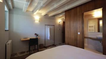 Quarto com cama, escrivaninha, cadeira, guarda-roupa de madeira e banheiro com pia e espelho.