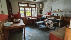Cozinha com janela, pia e prateleira com diversos objetos.