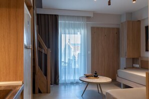 Um interior moderno com uma escada, uma mesa redonda com livros e um vaso, e um sofá.