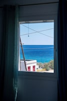 Uma janela com vista para o mar e um edifício com portas vermelhas.