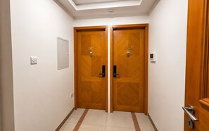 Corredor com duas portas de madeira numeradas 101 e 102, um interruptor de luz e um painel de segurança na parede.