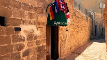 Um edifício de pedra com porta de madeira e toldo verde com bandeiras.