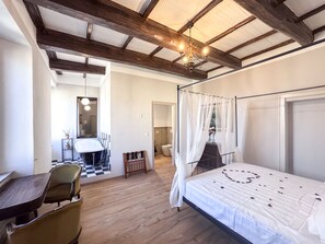 Quarto com cama, cadeira, mesa e espelho.