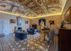 Um quarto luxuoso com piso estampado, lareira, sofá azul e teto com detalhes artísticos.