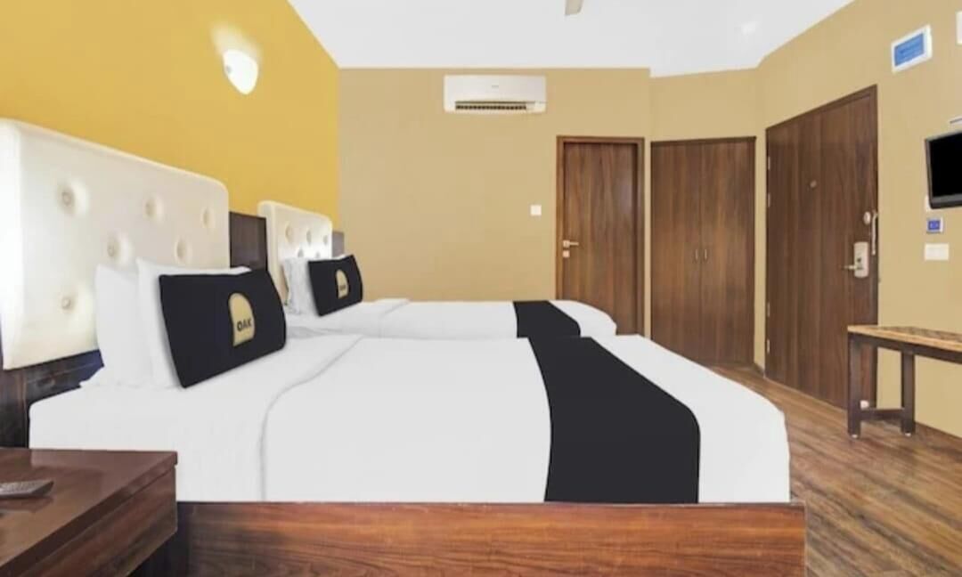 Quarto de hotel com uma cama grande, mesa de cabeceira, televisão e guarda-roupa.