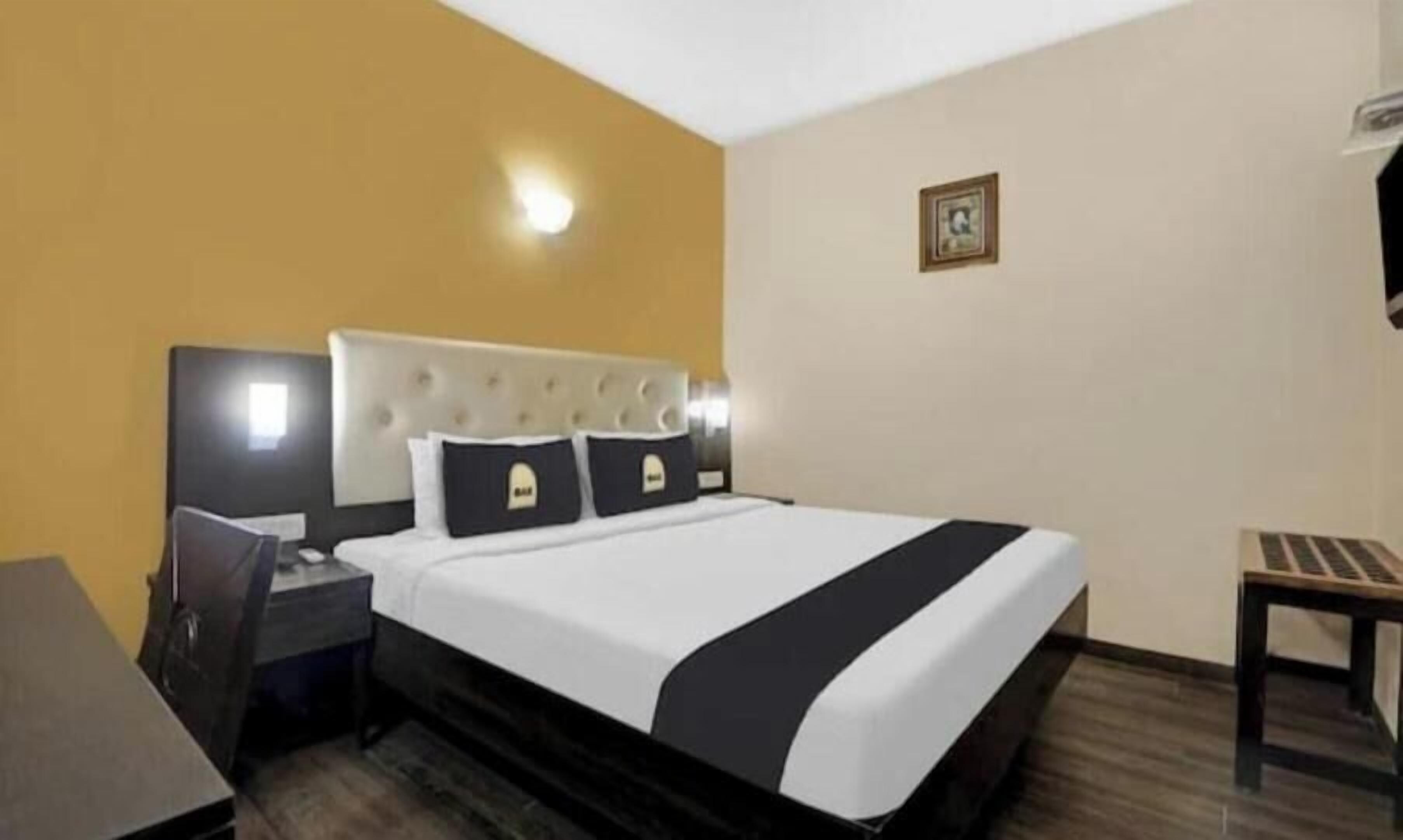Quarto de hotel com cama, mesas de cabeceira, escrivaninha e uma cadeira.