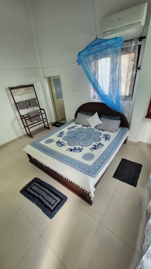Quarto com cama, cadeira suspensa, janela com cortina e ar condicionado.