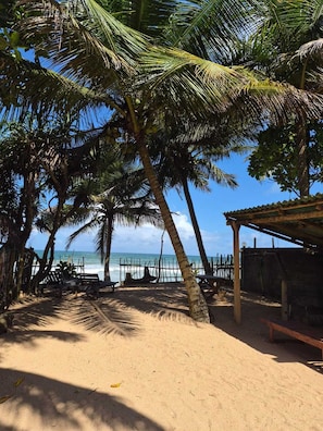 A beach with palm trees, a wooden structure, and a view of the ocean.