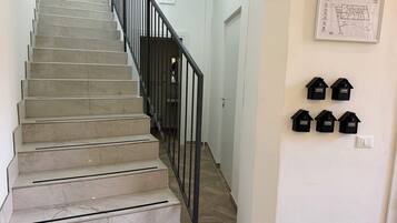 Escada com corrimão preto que leva a uma porta.