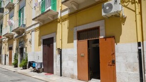 Uma fileira de edifícios com varandas, uma rua e um carro estacionado.