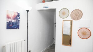 Um corredor com radiador, luminária, espelho emoldurado e objetos decorativos na parede.