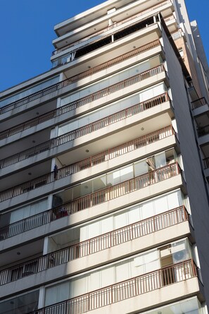 Um edifício de vários andares com varandas, janelas amplas e um céu claro.