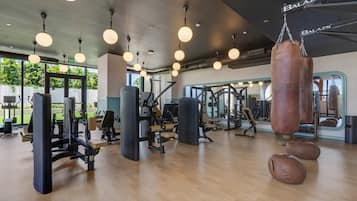 Uma academia com diversos equipamentos de exercício, incluindo máquinas de peso e um saco de pancada.
