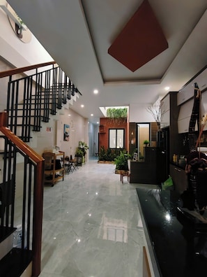 Amplo espaço interior com escadas, balcão de recepção e área de estar.
