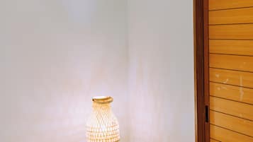 Quarto com cama, mesa de cabeceira com abajur e guarda-roupa de madeira.
