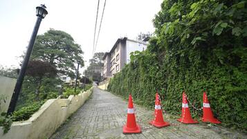 Uma passarela pavimentada com cones de trânsito, um poste de luz e um edifício ao fundo.