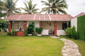 Uma casa com telhado vermelho, varanda frontal e um caminho que leva à entrada.