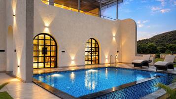 Um edifício moderno com piscina, área de estar ao ar livre e vista para a paisagem circundante.