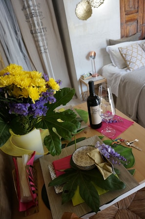 Uma mesa com uma garrafa de vinho, uma taça, uma tigela e um buquê de flores.