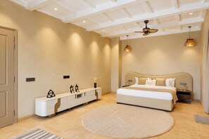Quarto com cama, mesas de cabeceira, ventilador de teto e luminária na parede.