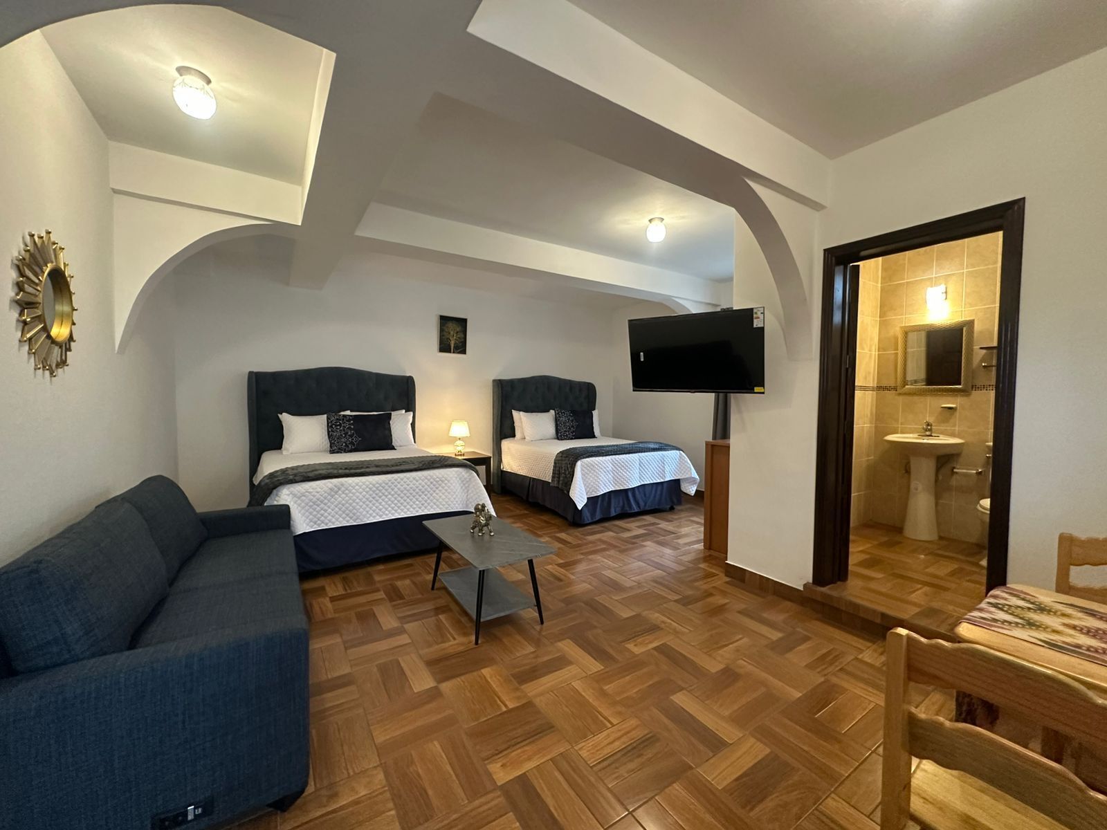 Quarto de hotel com duas camas, um sofá, uma televisão e uma casa de banho.