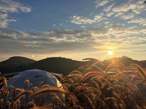 Vista do pôr do sol com céu claro, um corpo d'água e uma cadeia de montanhas ao longe.