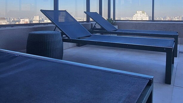 Uma área de estar no terraço com espreguiçadeiras e vista para a cidade.
