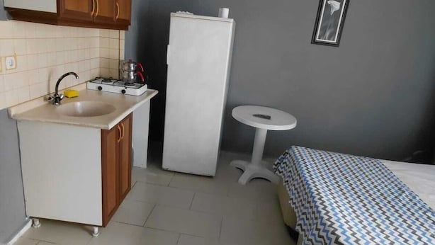 Uma cozinha compacta com pia, fogão e geladeira. Uma mesa redonda pequena fica ao lado da geladeira.