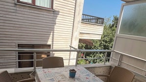 Um alpendre coberto com mesa e cadeiras, vista da casa, e céu limpo.