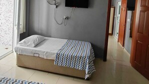 Quarto com cama, ventoinha, televisão fixada na parede e luminária de teto.